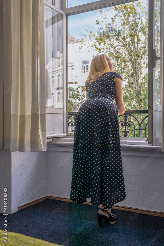 Blonde woman at the window. Young woman female with blonde long hair in ...