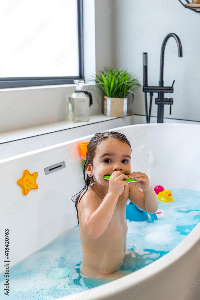 Girl in bathtub with toy in her mouth Stock Photo | Adobe Stock