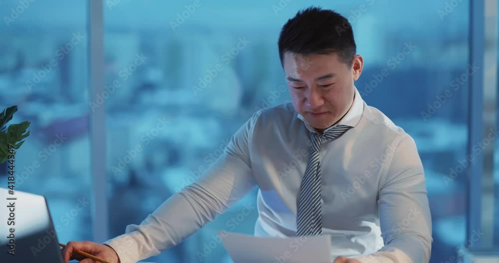 Chinese workaholic male adult businessman working with paper documents ...