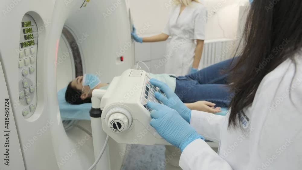 Female patient is undergoing CT or MRI scan under supervision of two ...