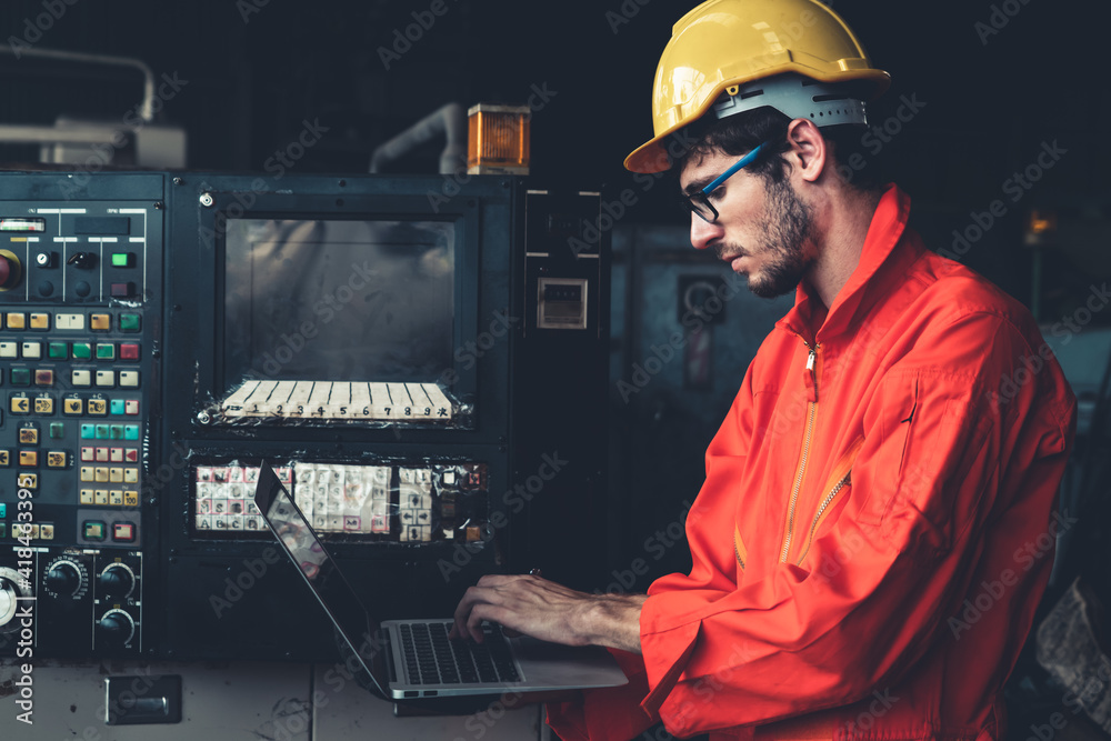 Skillful factory worker working with laptop computer to do procedure ...