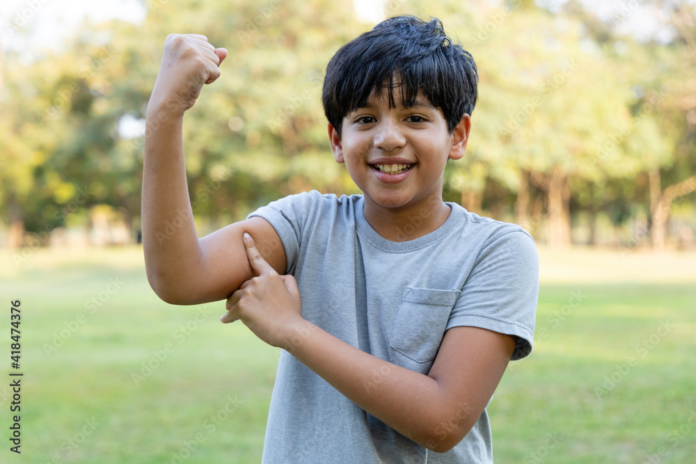 Indian boy showing muscles of the arm in the park. Concept of health ...