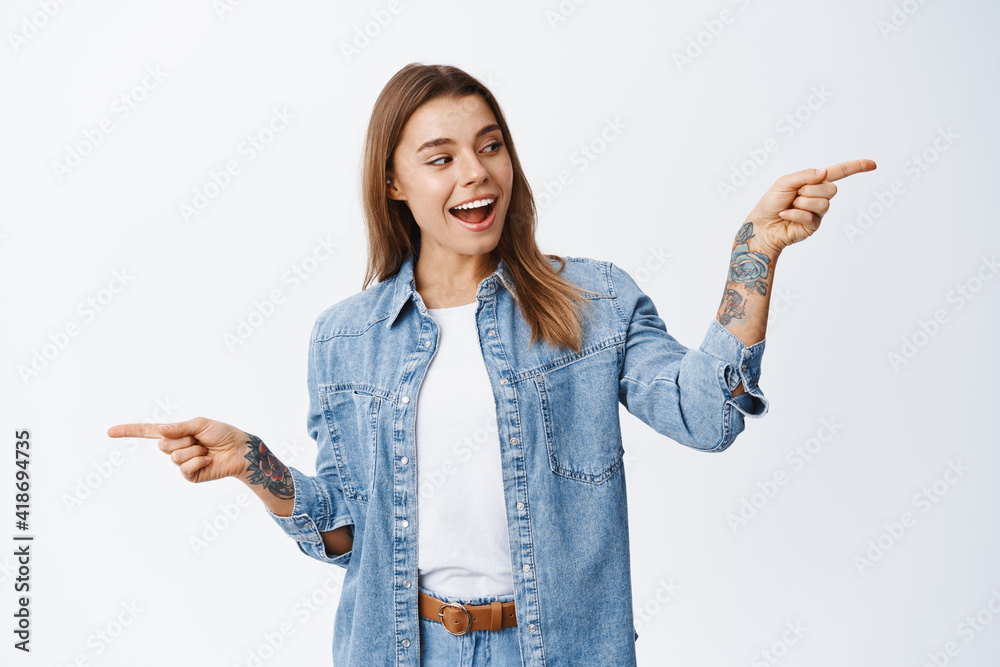 Blond young woman customer making choice, pointing and looking right ...