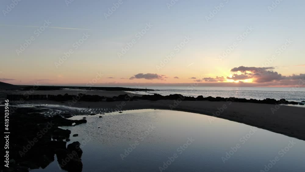 4k dynamic aerial video of sunset on a sand beach with shallow ponds of ...