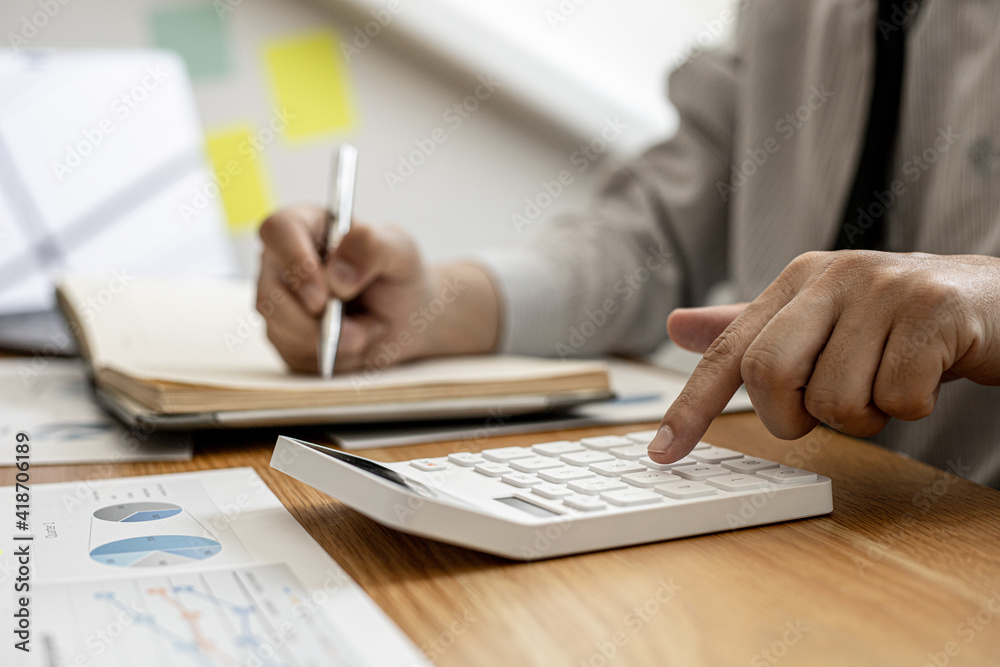 Businessman pressing a calculator to calculate numbers from the company ...