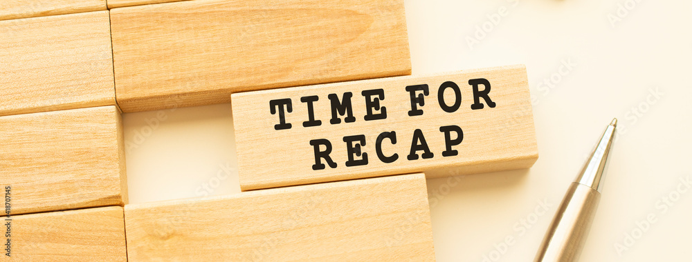 TIME FOR RECAP text on a strip of wood lying on a white table with a ...