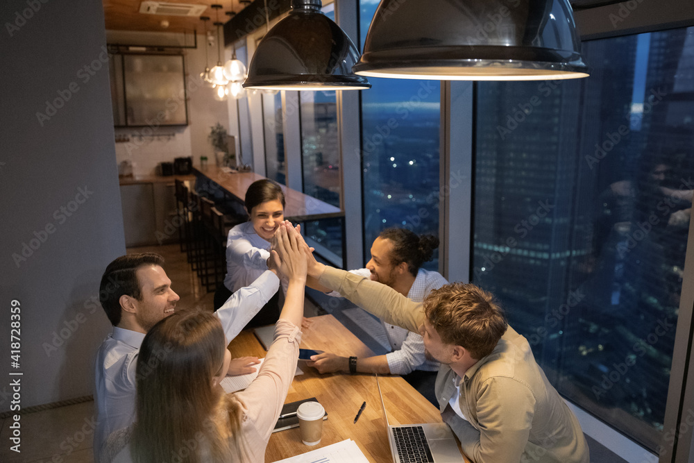 Top view overjoyed diverse employees giving high five at late corporate ...