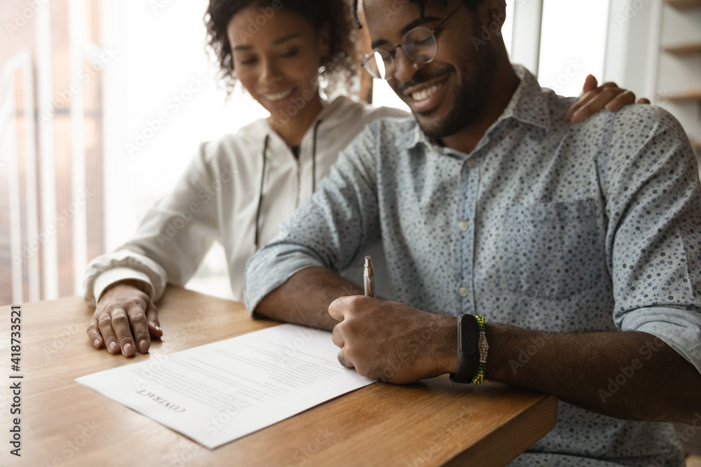 Close up smiling African American family signing contract, making ...