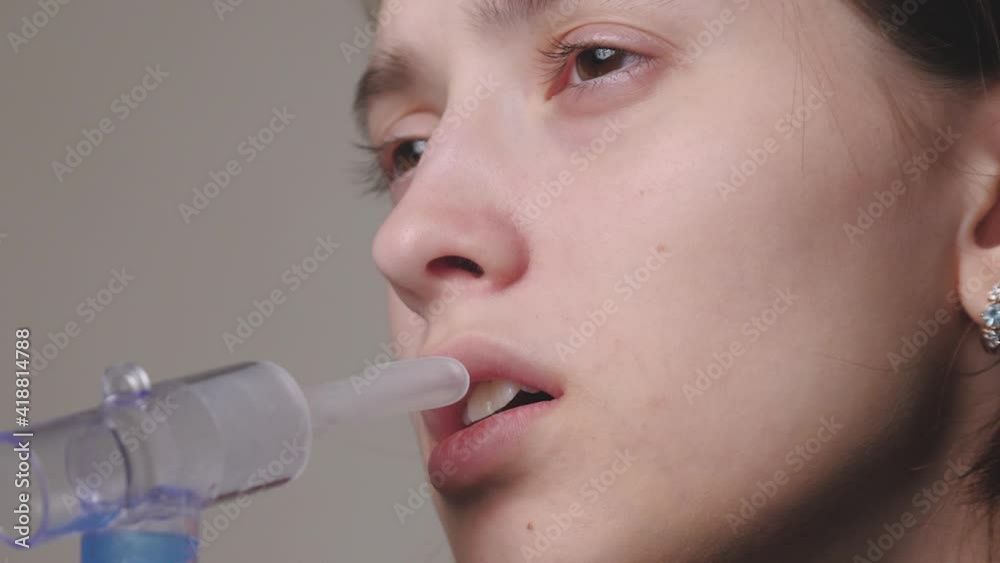 The girl breathes in a solution for inhalation of lungs. A young woman ...