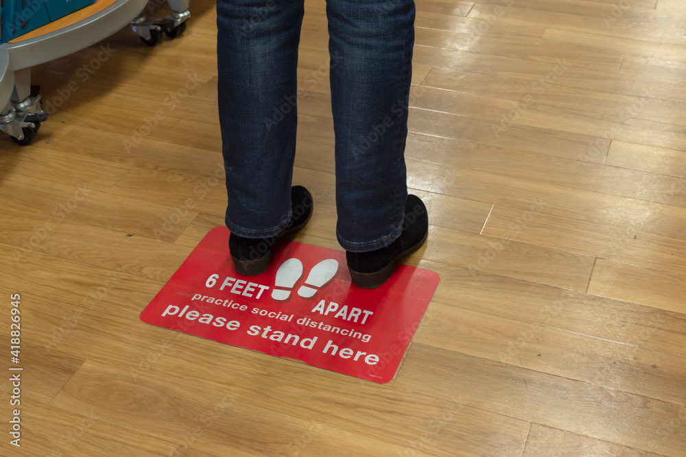 Person waiting in line standing on Six Feet Apart Social Distancing red ...