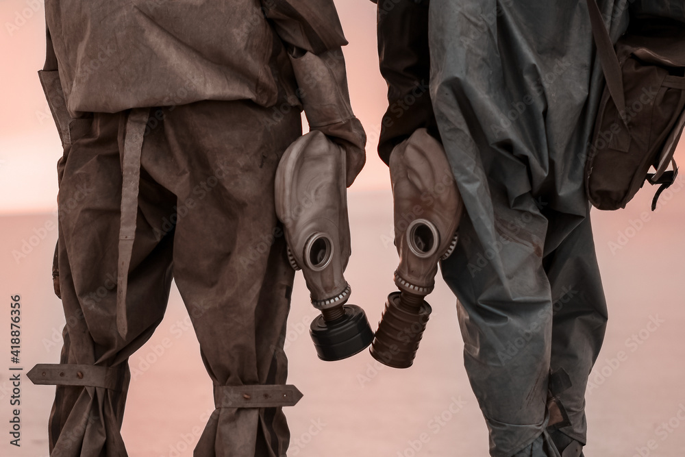 Two people with gas masks and chemical protection suits on the ...