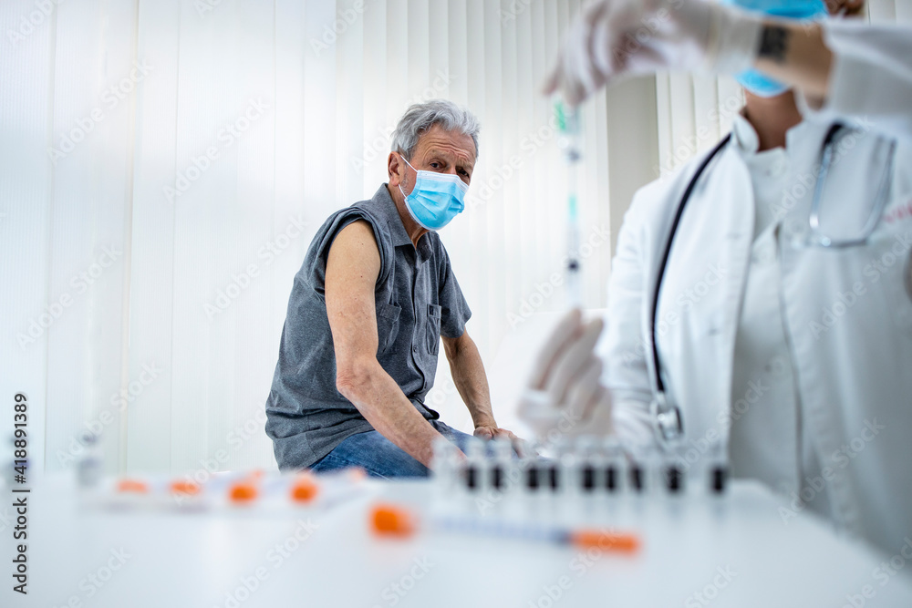 Senior man about to get vaccine shot in the clinic during corona virus ...