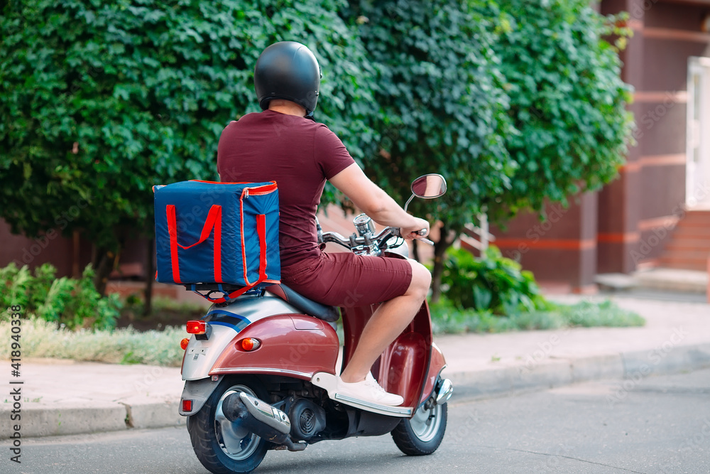 Foto de Delivery boy wearing red uniform on scooter with isothermal ...