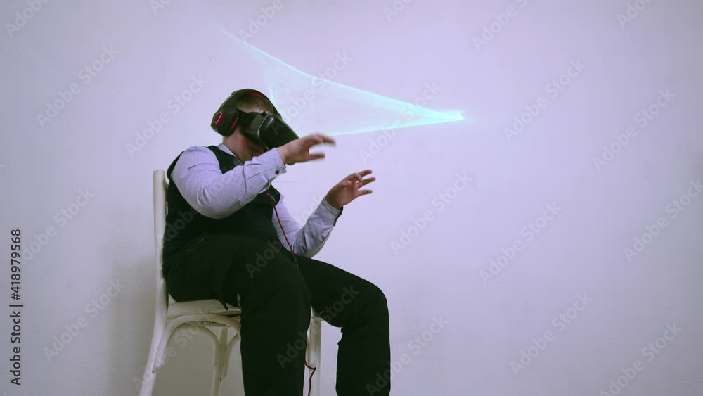 A boy in a virtual reality headset and headphones plays while sitting ...