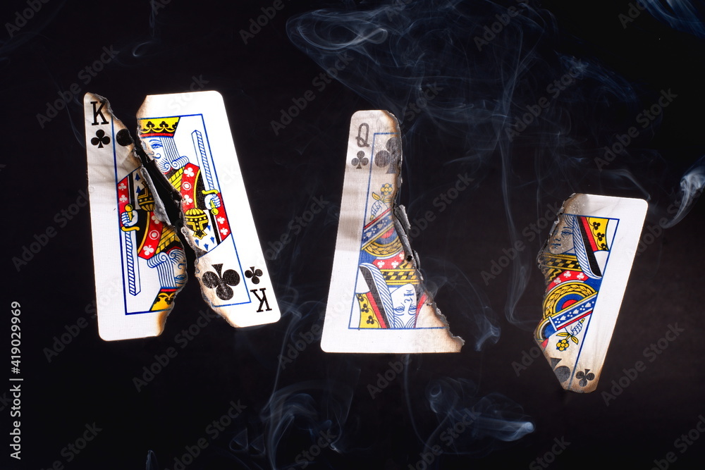 Abstract smoke patterns wafting upwards from two burnt playing cards ...