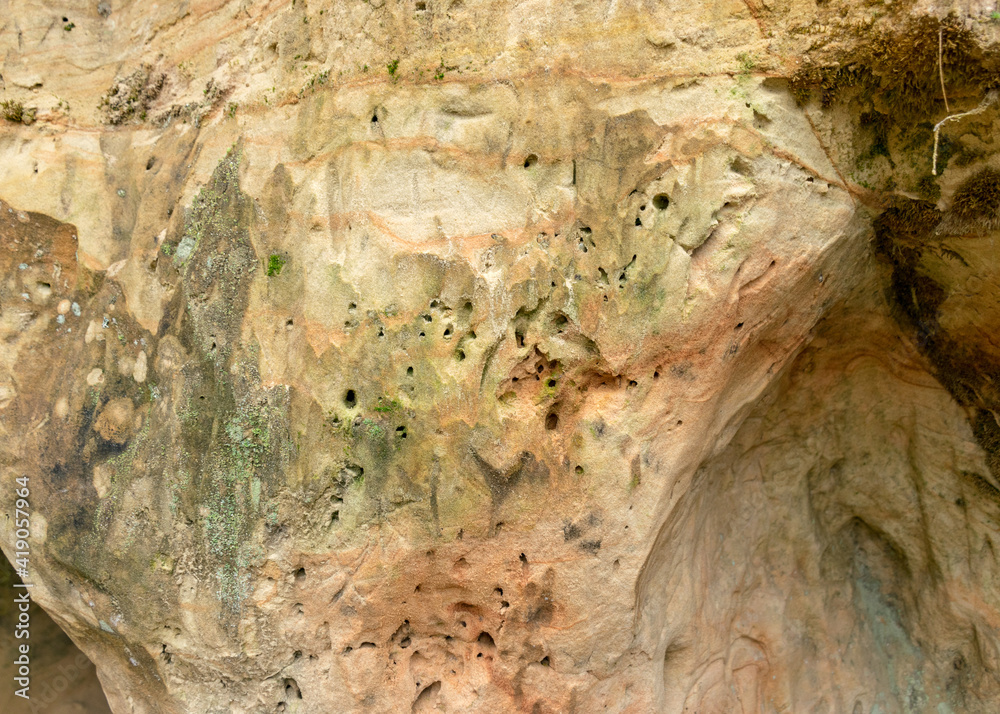 sandstone rock wall and entrance to the cave, the cave is located on ...