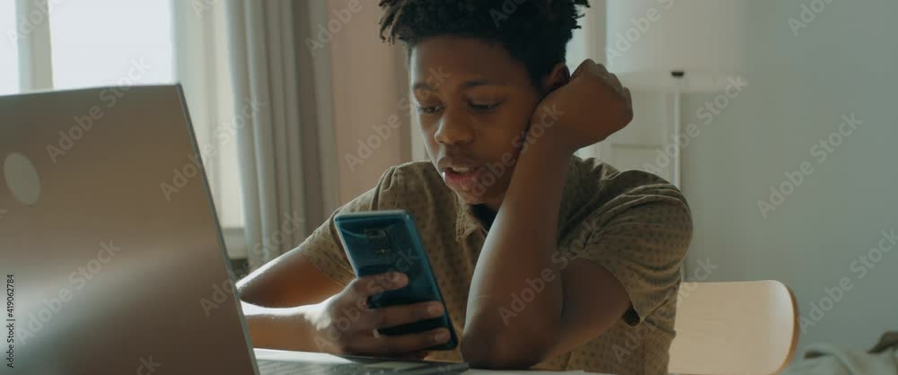 DX Portrait of African American Black kid boy using his phone at home ...