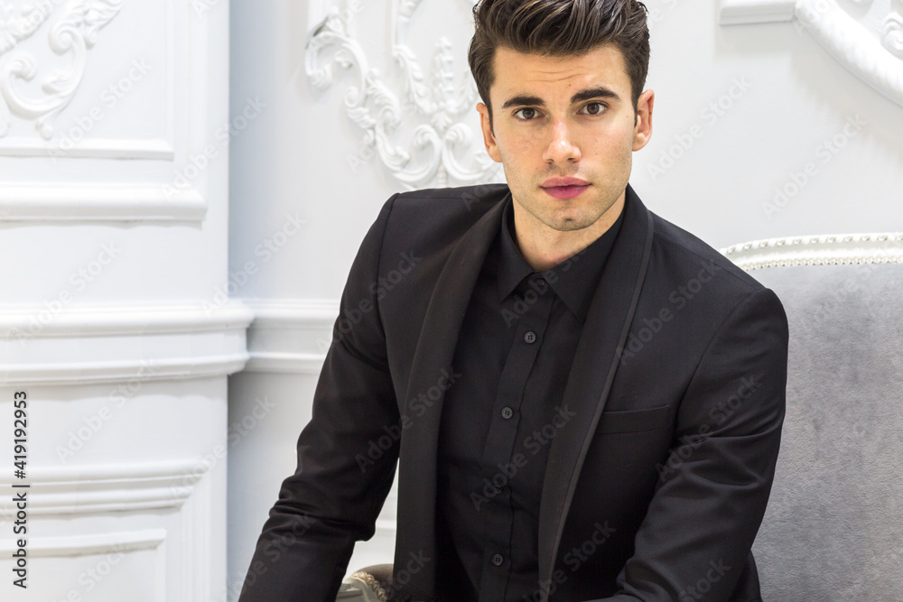 Elegant handsome male model wearing a businessman suit sitting in a ...