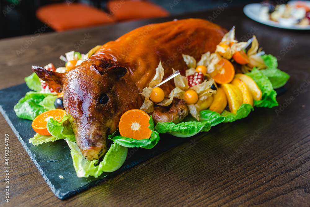 Restaurant menu. Baked suckling pig whole on a stone decorative board ...