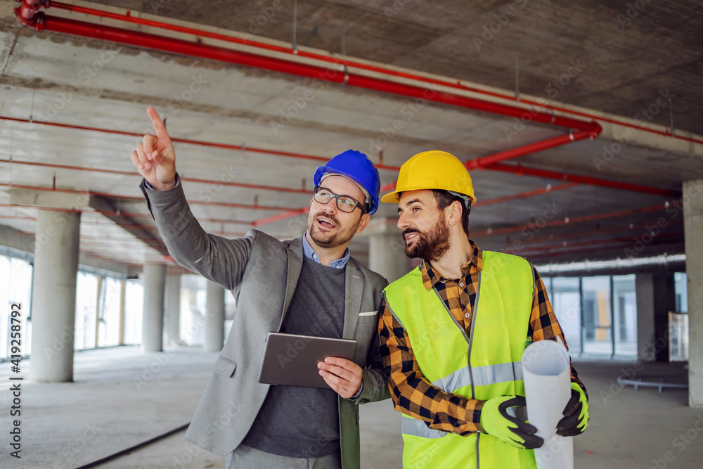 Construction worker and architect standing in building in construction ...