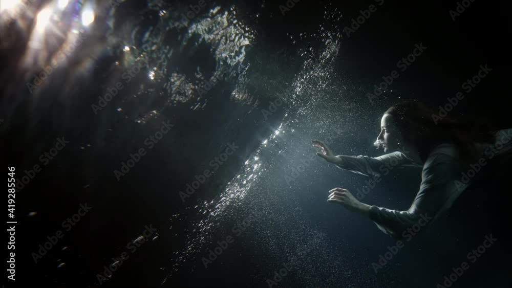 mystery and magic underwater, young woman is floating to mirror water ...