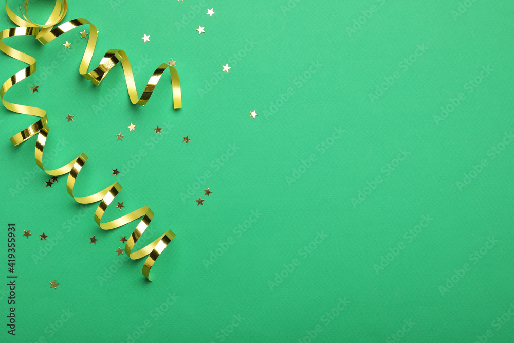 Shiny golden serpentine streamers and confetti on green background ...