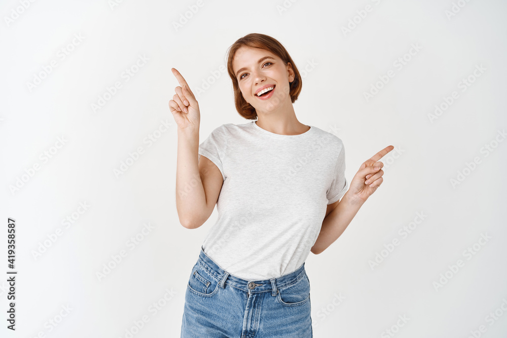 Portrait of young carefree woman pointing at two sides directions. Girl ...