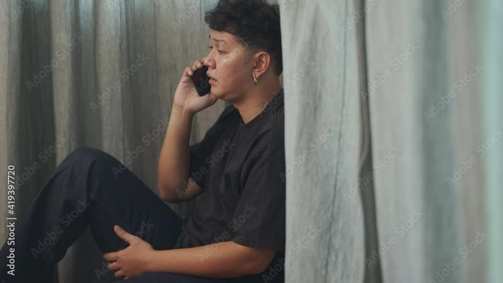 Stressed Asian man sit on the floor with talking on mobile phone and ...