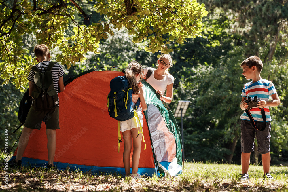 School kids setup a camping tent with their female teacher. foto de ...