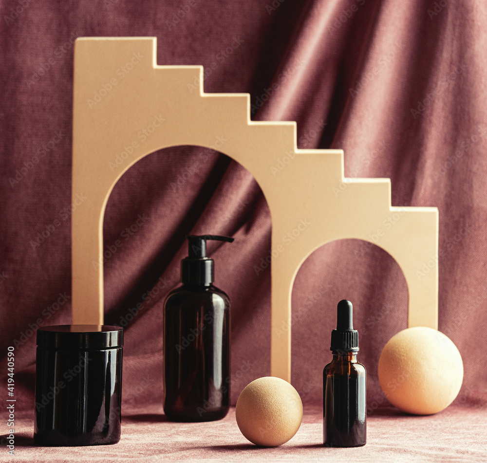 presentation of dark cosmetic containers next to golden geometric ...