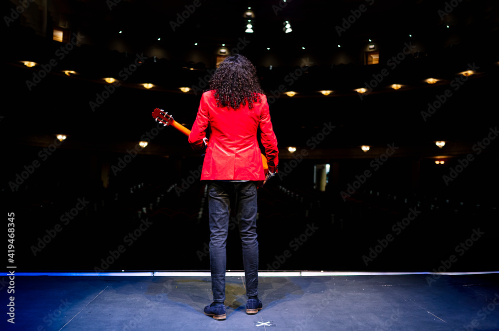 Full body of male musician standing on stage and playing guitar during ...