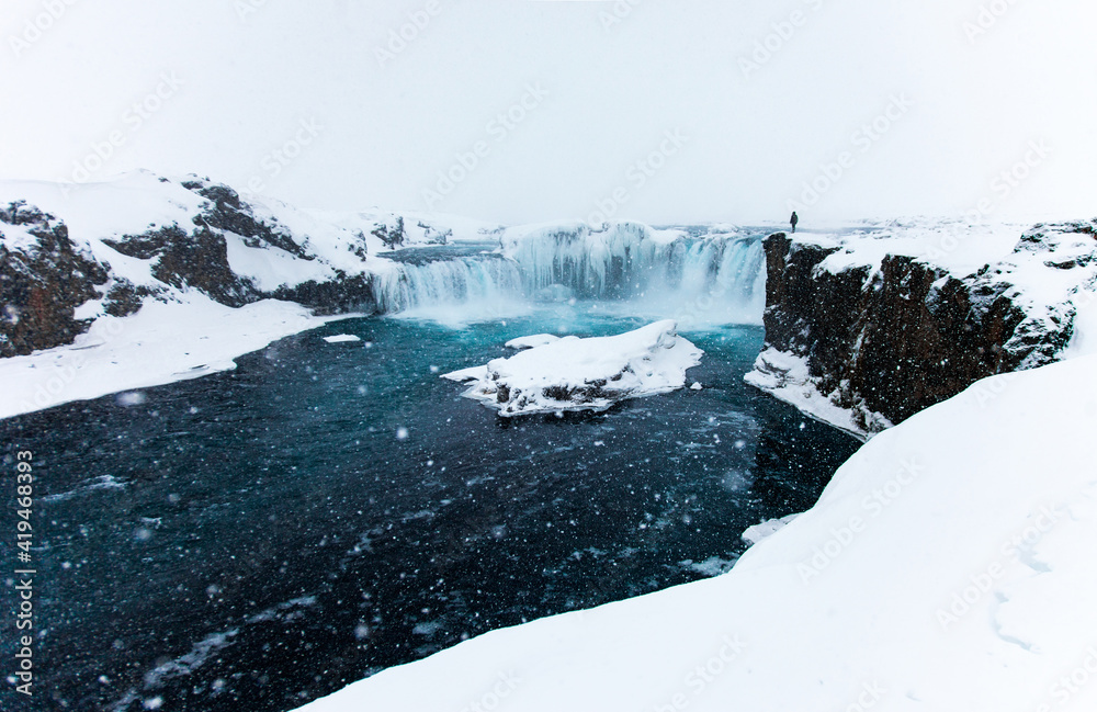 Distant view of explorer standing on edge of cliff and admiring scenery ...