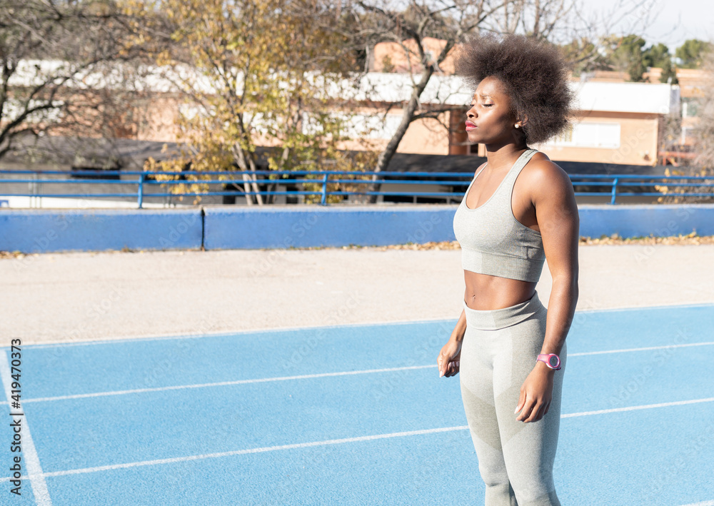 Side view of concentrated African American runner standing on track and ...