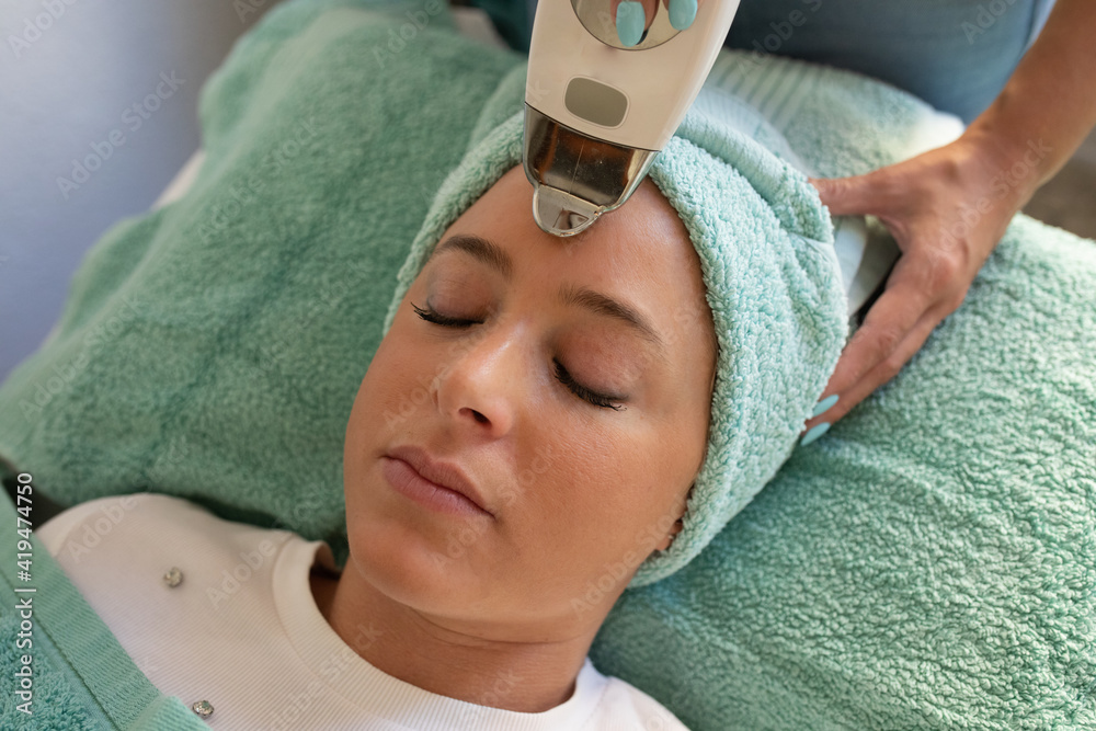 High angle of crop unrecognizable female cosmetician doing laser ...