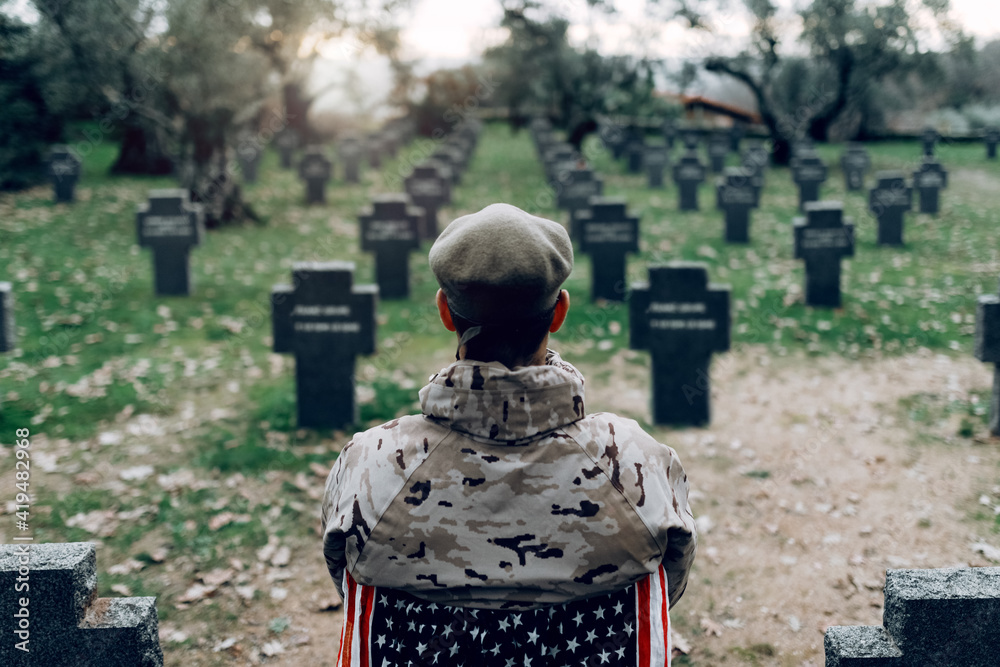 Back view of soldier in uniform sitting on chair with American flag ...