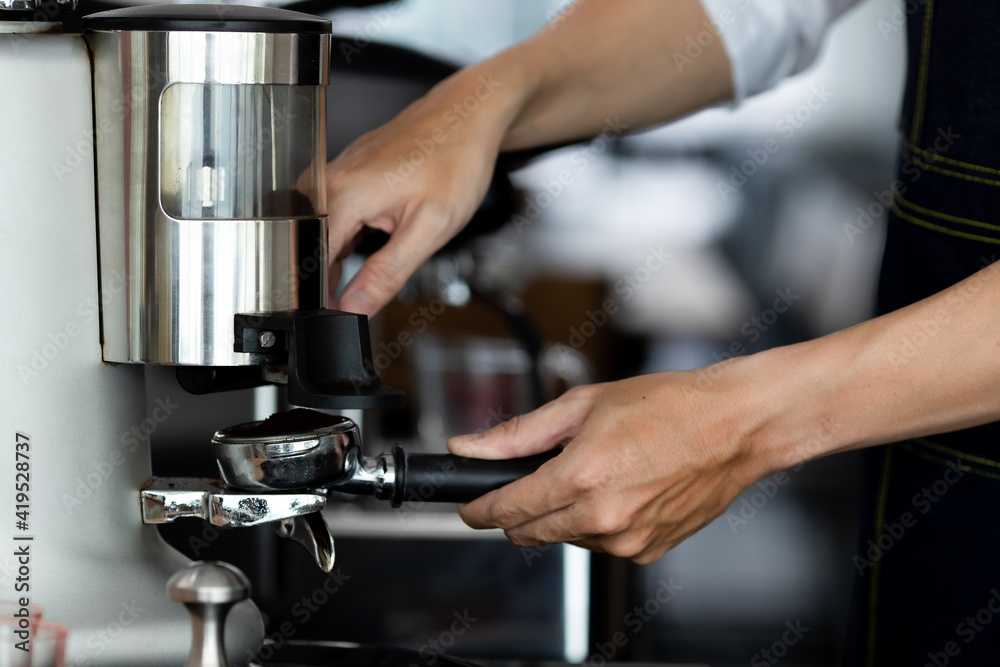 close up photo of male hands holding a metal tamper and a portafilter ...
