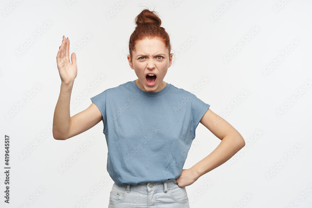 Teenage, angry looking woman with ginger hair gathered in a bun ...