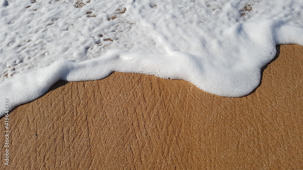 natural white foam of wave on beach sand, close up background with copy ...