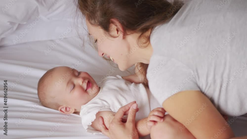 Loving young mommy hugging soothing adorable sweet baby girl lying in ...