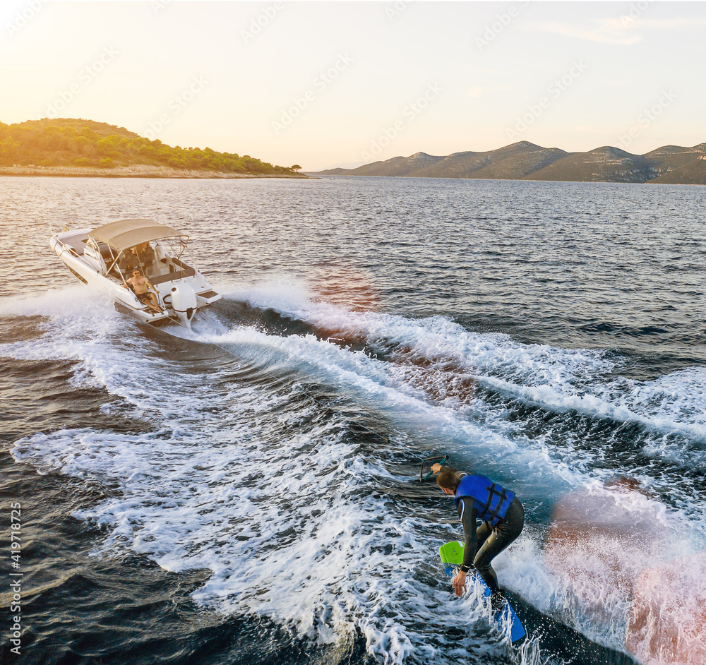 Aerial photo of man practicing wakeboarding towed by speed boat in deep ...