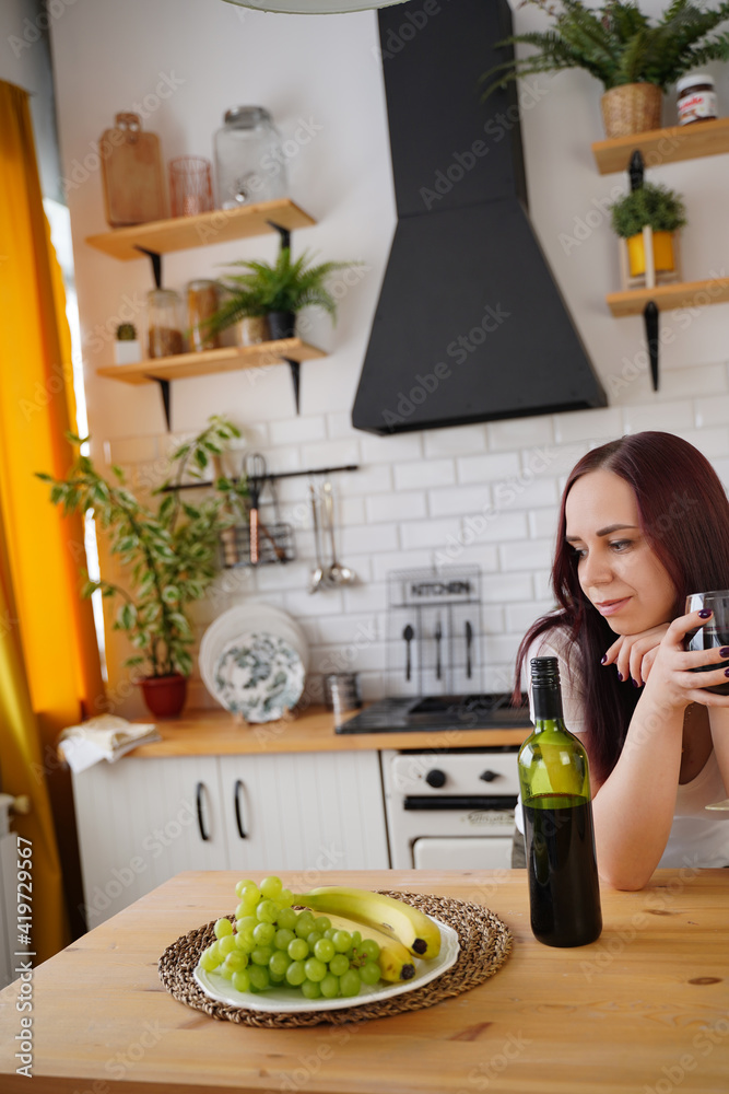 Relaxed young woman poses, standing at kitchen table. Adult brunette ...