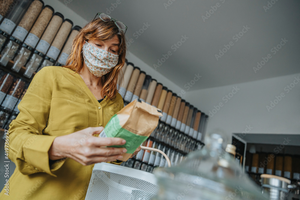 Female customer checking label on food package while shopping in retail ...