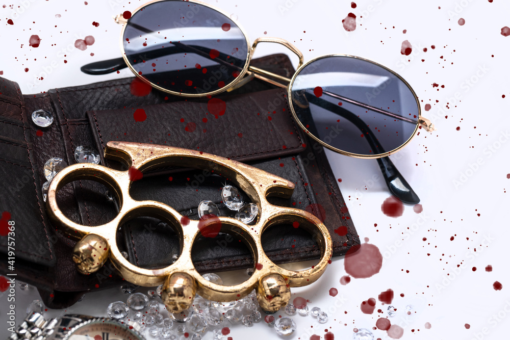 Drops of blood on Sunglasses and brass knuckles watch between crystal ...
