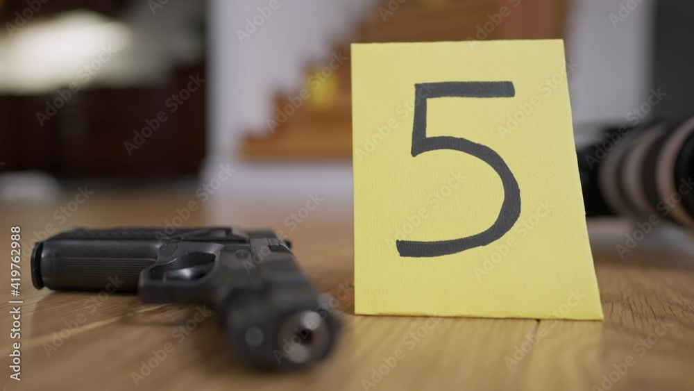 Close-up of gun lying on the floor as female hand in protective suit ...