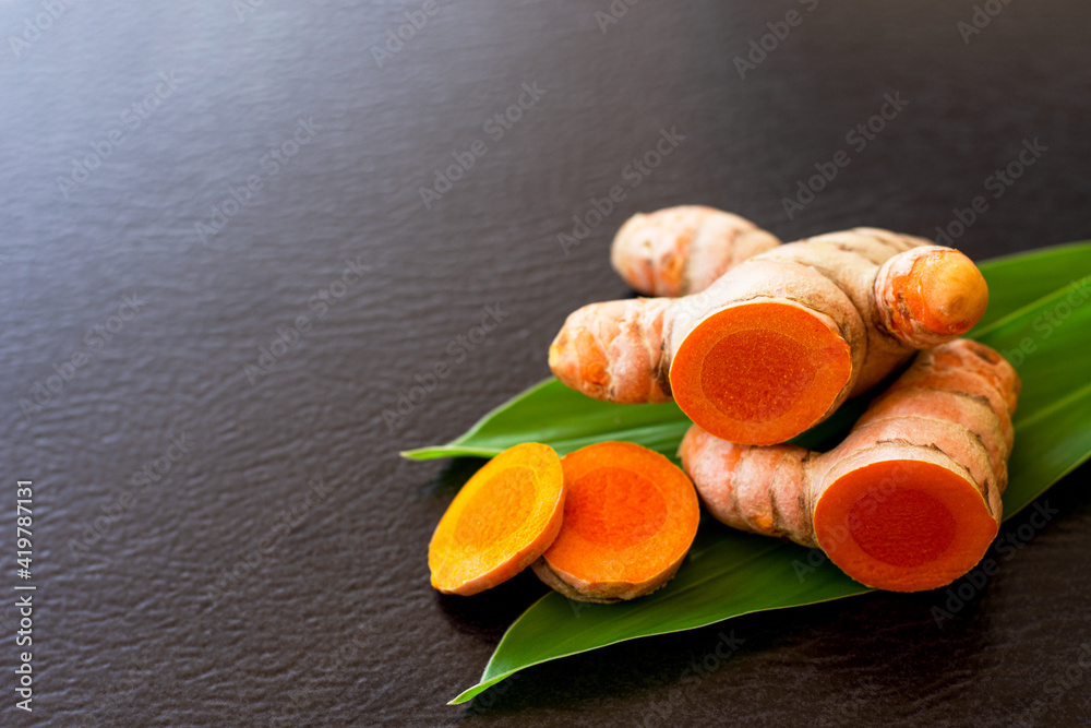 Tumeric ( Turmeric ) root with green leaf and slice isolated on dark ...