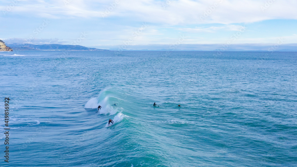 Aerial drone view of surfers riding perfect swell waves in the beach of ...