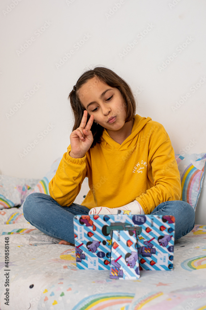 Little Caucasian girl, with a cast in one hand, making a video call ...