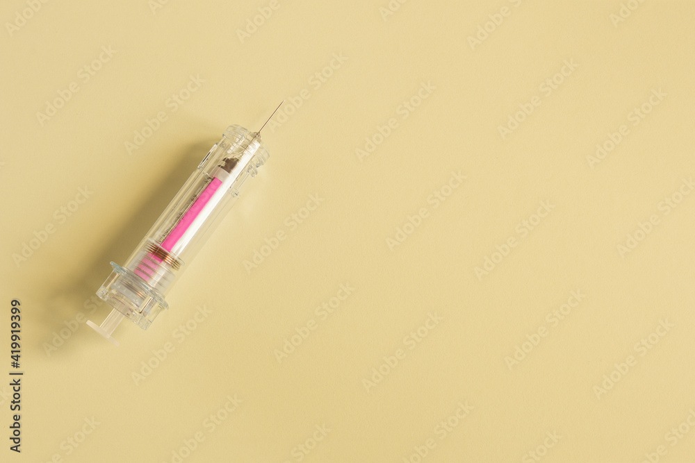 A colorful isolated pink syringe with the needle uncapped on textured ...