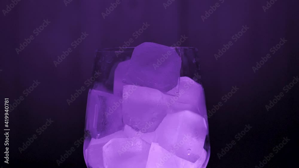 Purple ice cubes falling into a glass for an alcoholic, non-alcoholic ...