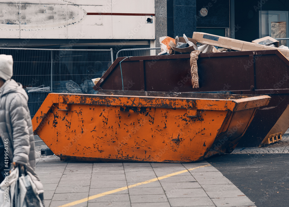 Waste and recycling orange skip next to construction site in the city ...